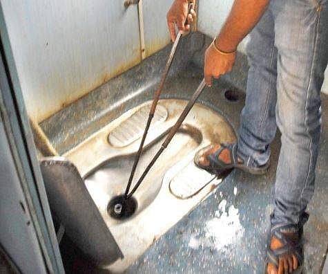 Manual scavengers give a hand to clean clogged up bio-toilets