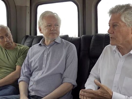 Why is Julian Assange flying to the remote Pacific island of Saipan?