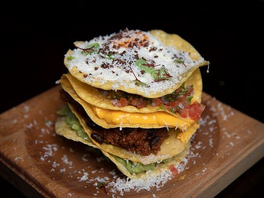 Cheesy nachos tower with chili con carne topped with an egg